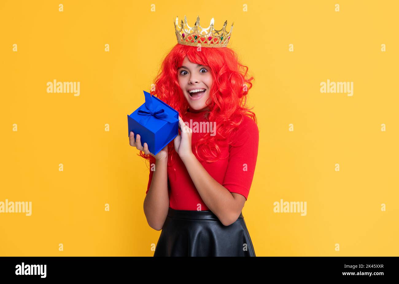 shocked kid in crown with present box on yellow background Stock Photo ...