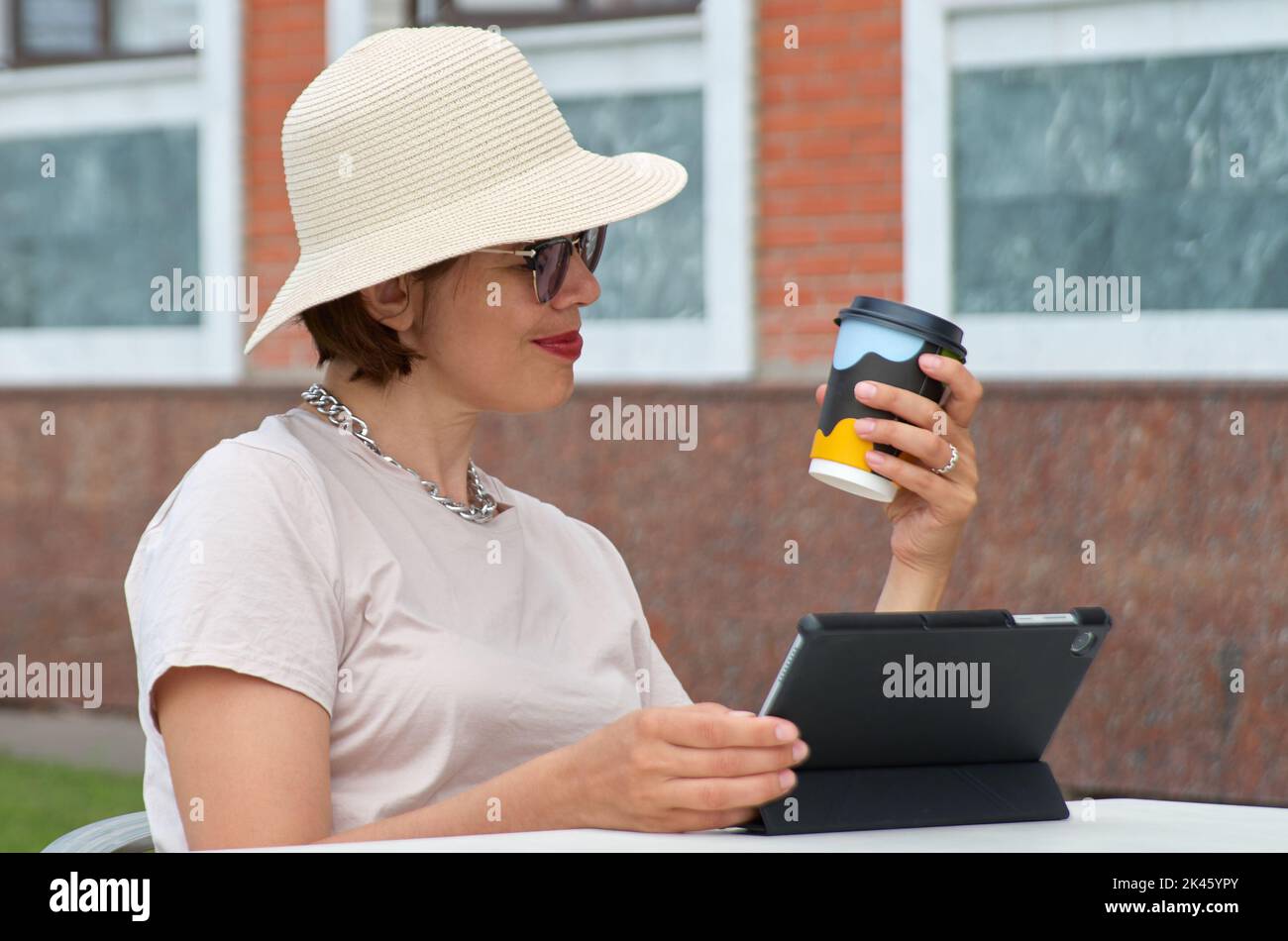 Woman using tablet computer and drink coffee at sidewalk cafe Stock ...