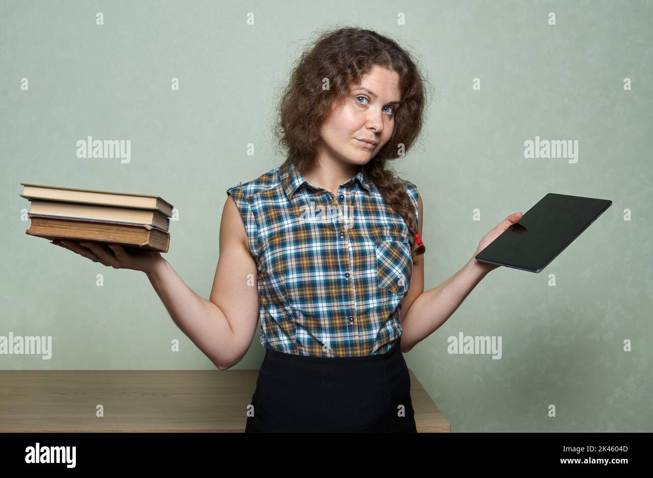 Book vs digital tablet. A woman makes a choice between books in one of ...