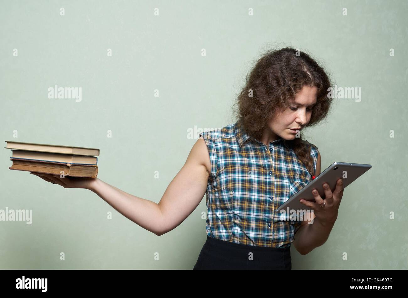 Book vs digital tablet. A woman makes a choice between books in one of ...
