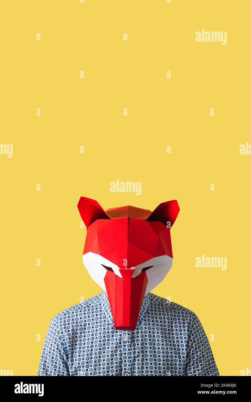 frontal view of a man wearing a red and white fox mask, looking down ...