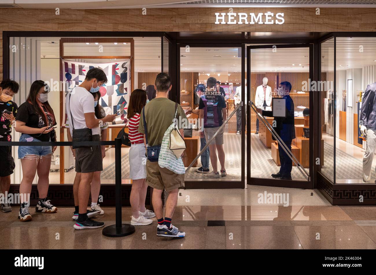 Shoppers queue in line to enter the French high fashion luxury clothing ...