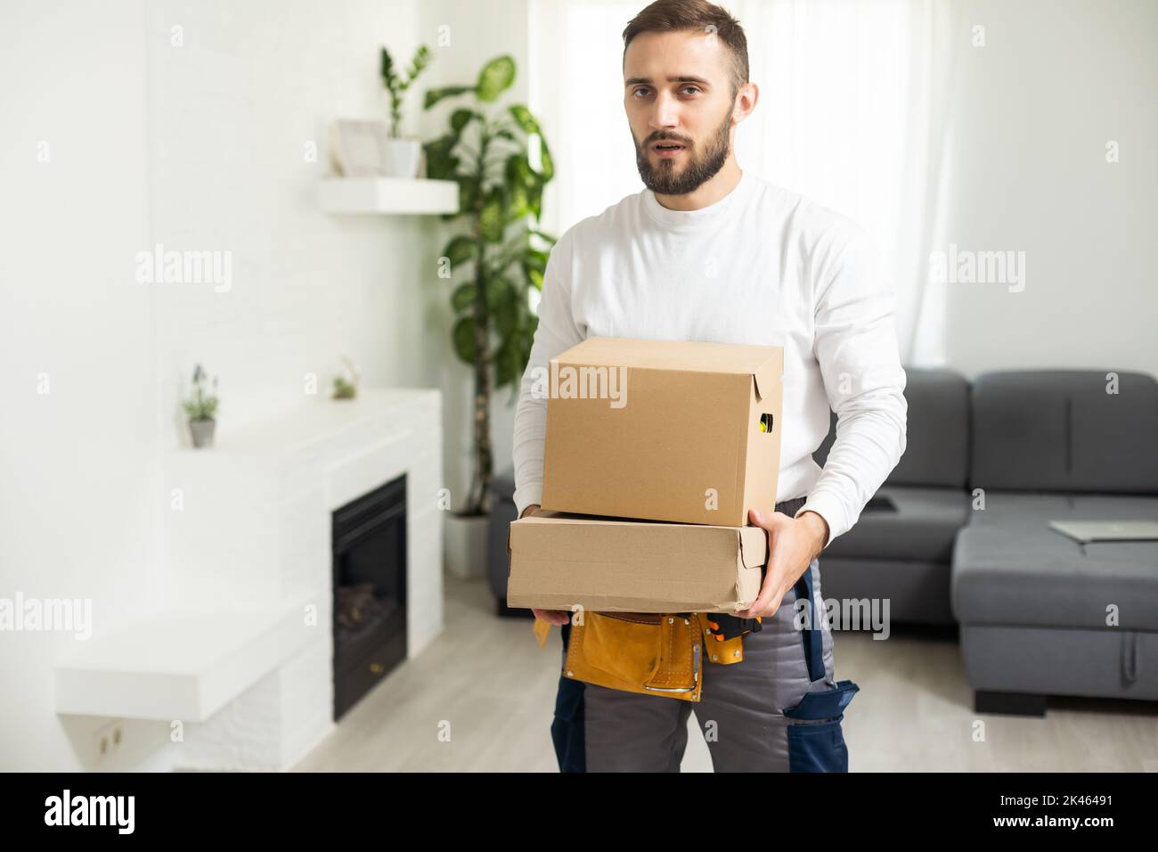 Young smiling logistic delivery man in uniform holding the box on white ...