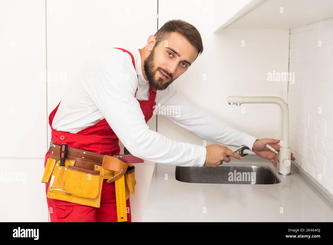 Side View Of A Plumber Fixing Water Tap In Kitchen Stock Photo - Alamy