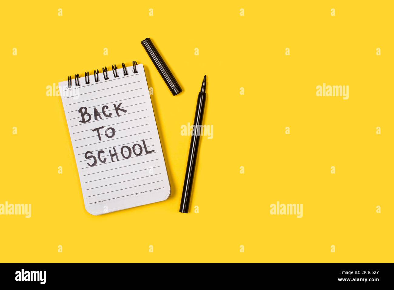 Back to school write in a lined notepad and a black marker on a yellow ...