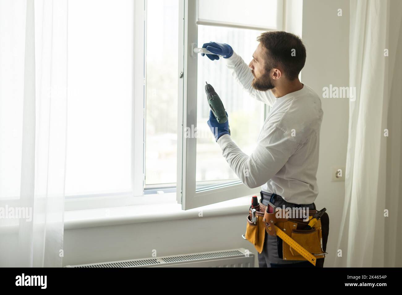 handsome young man installing bay window in a new house construction ...