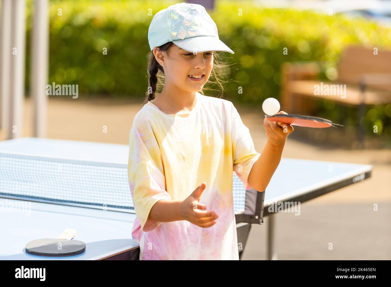 Young teenager girl playing ping pong. She holds a ball and a racket in ...