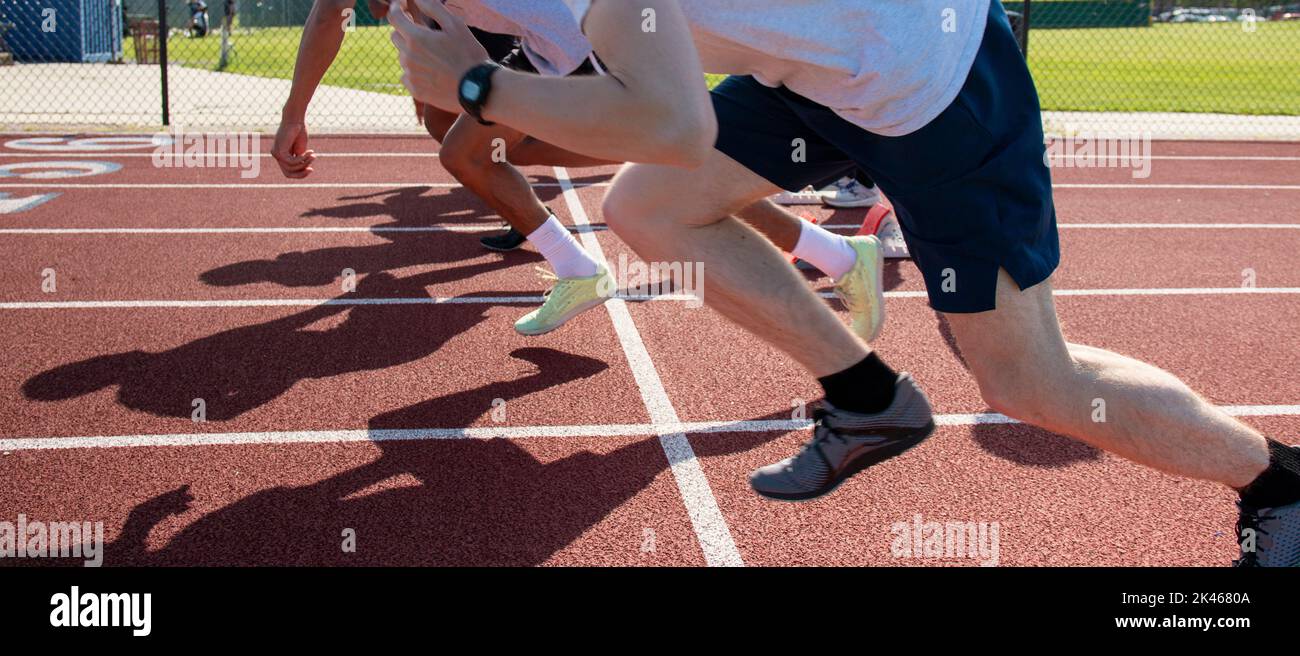 Side view of a group of high school sprinters starting a race against ...