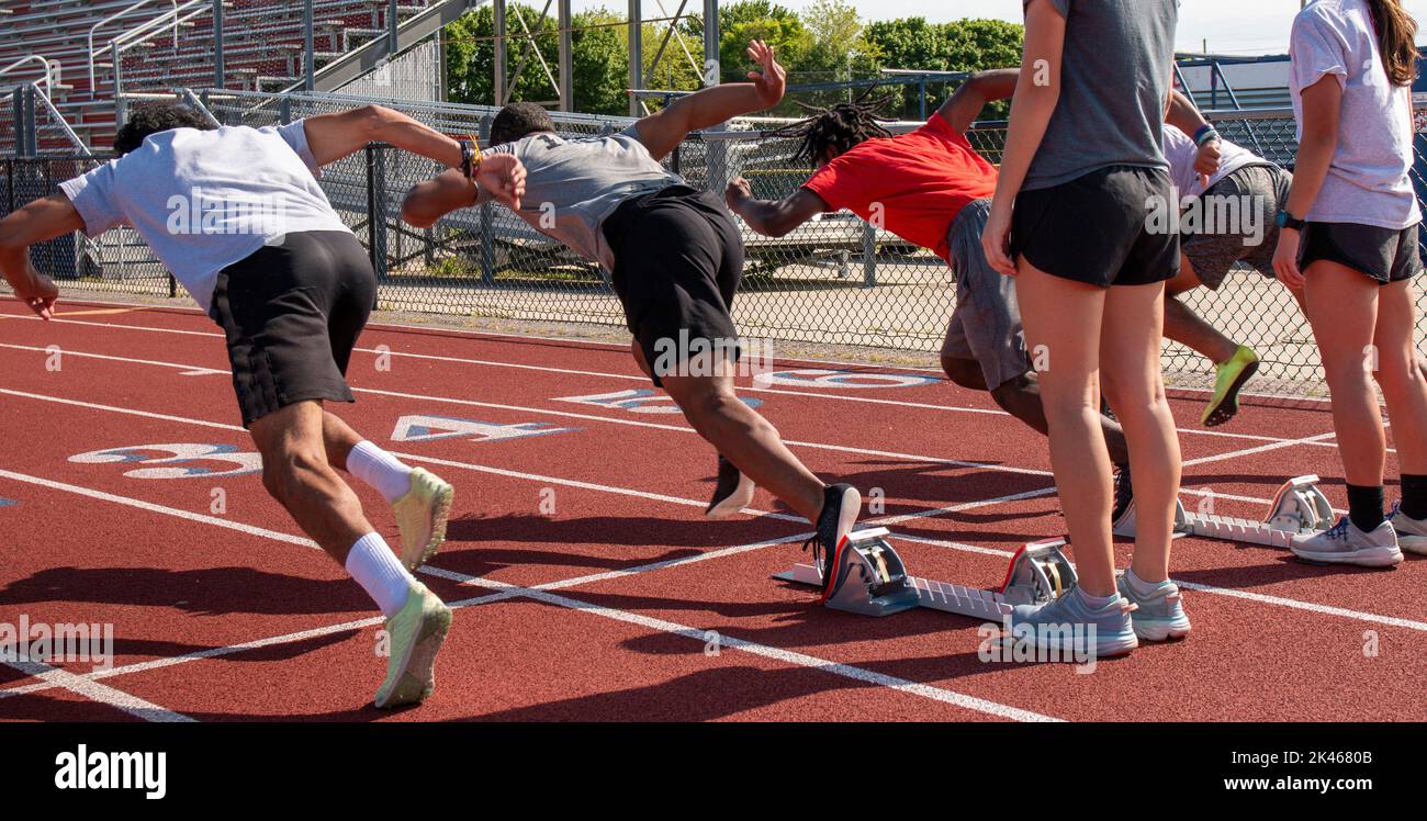 Rear view of High school track runners racing each other from the ... Rear view of High school track runners racing each other from the ...