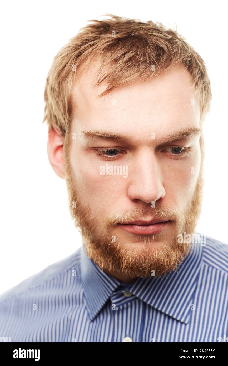 Ruggedly handsome. An unshaven young man looking down isolated on white ...