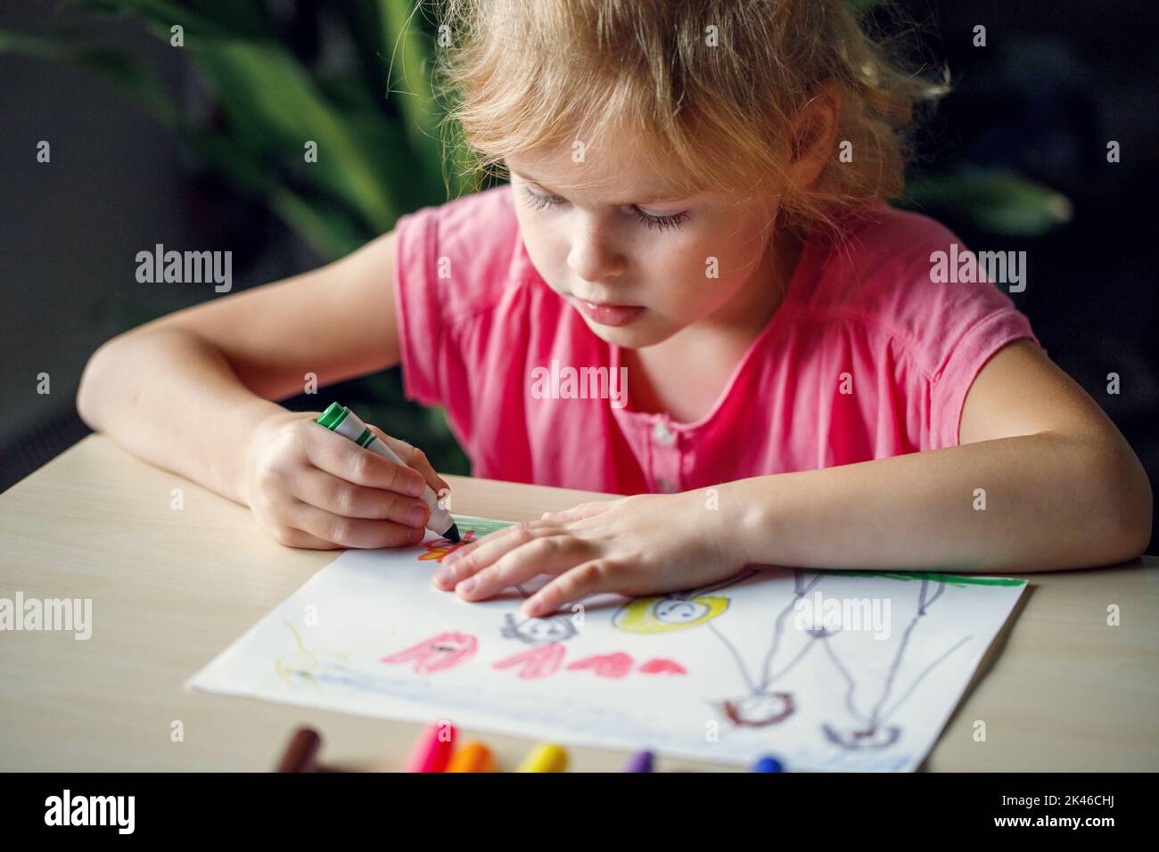 Child drawing a picture of her family with colored markers. Little girl ...