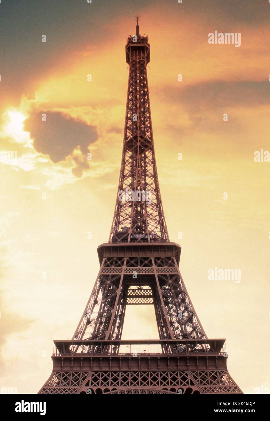 Eiffel Tower complete structure at dawn with yellow sky and dark clouds ...