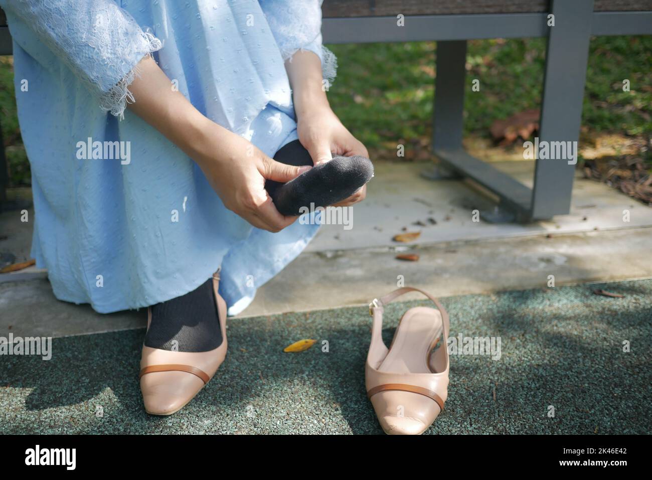 women hand messaging on her feet sitting on park bench Stock Photo - Alamy