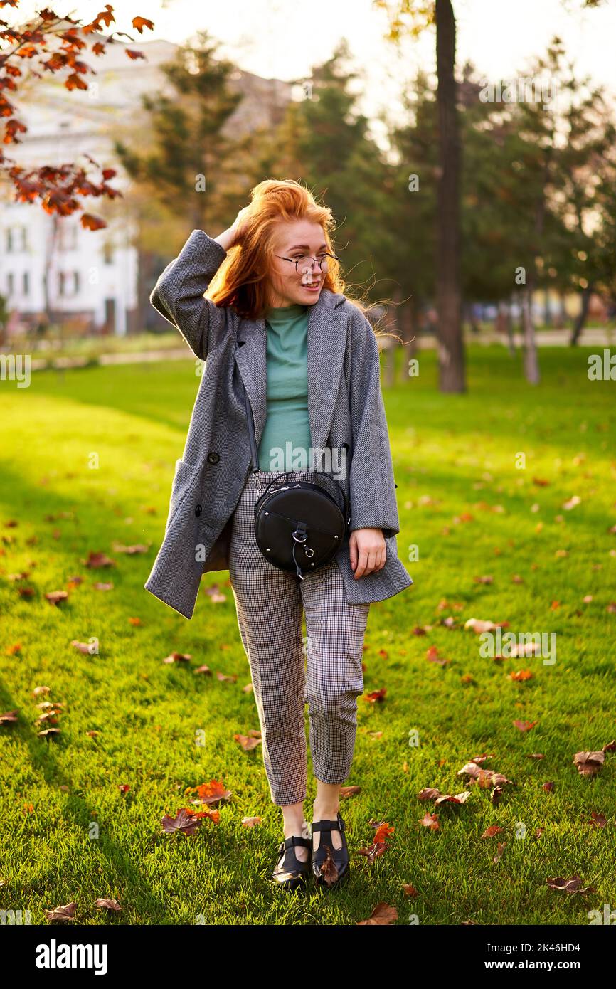 Redhead smiling pretty woman walking in park on sunny autumn day ...