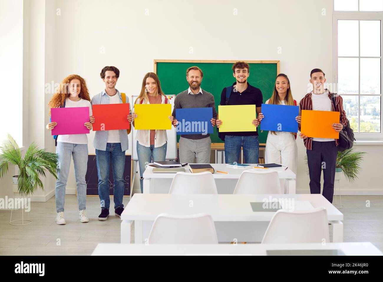 Smiling students and their male teacher holding colorful paper posters ...