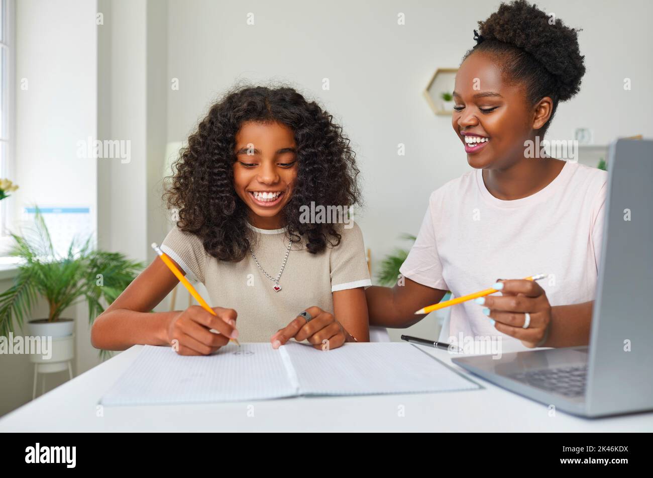 Caring and friendly mother helps her daughter to do homework that was ...
