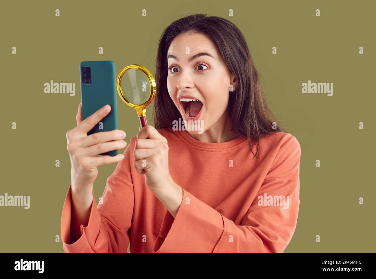Woman looking at smartphone through magnifying glass with funny happy ...