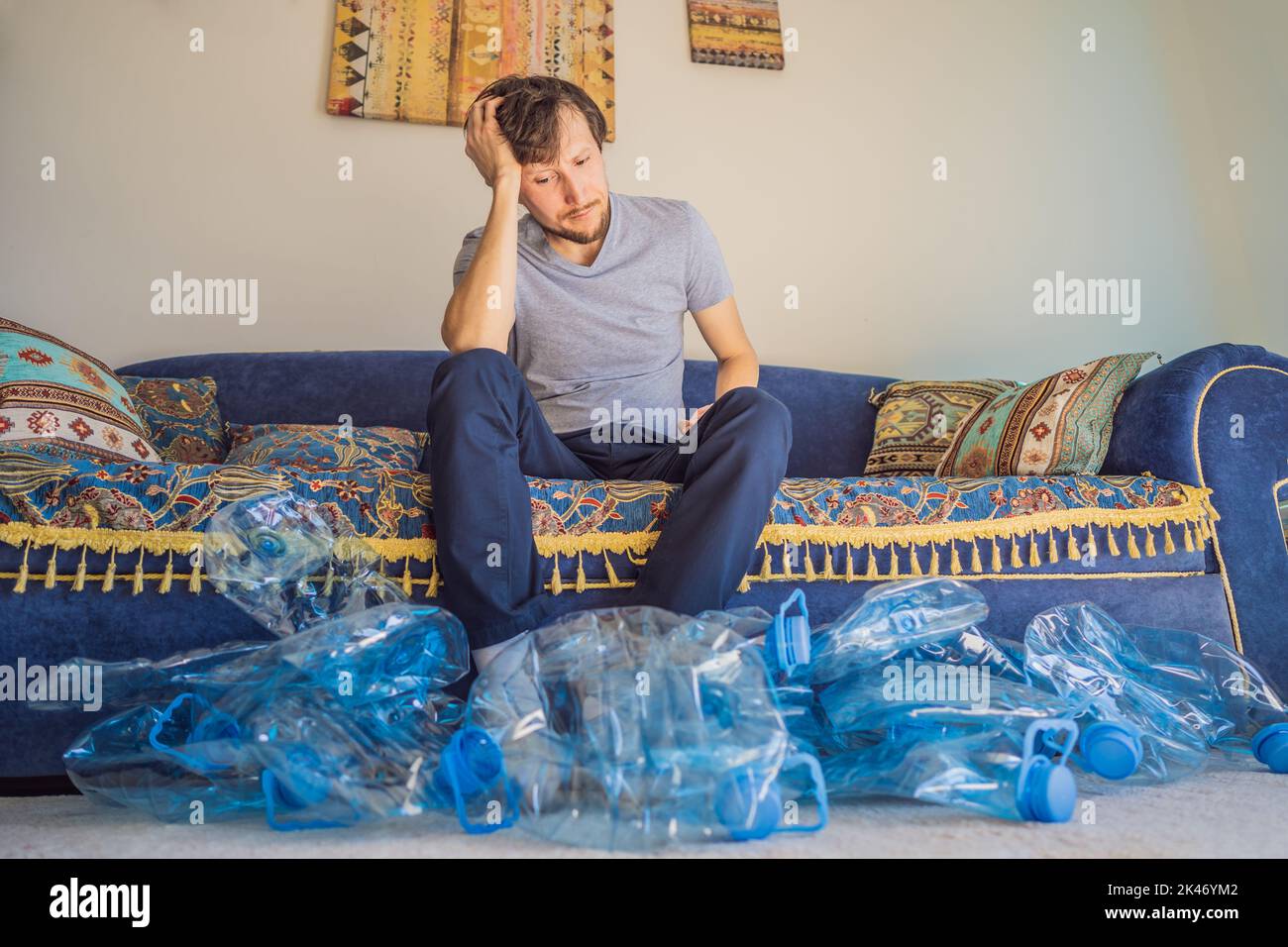 Young caucasian man hamong empty plastic bottles to recycle with sad ...