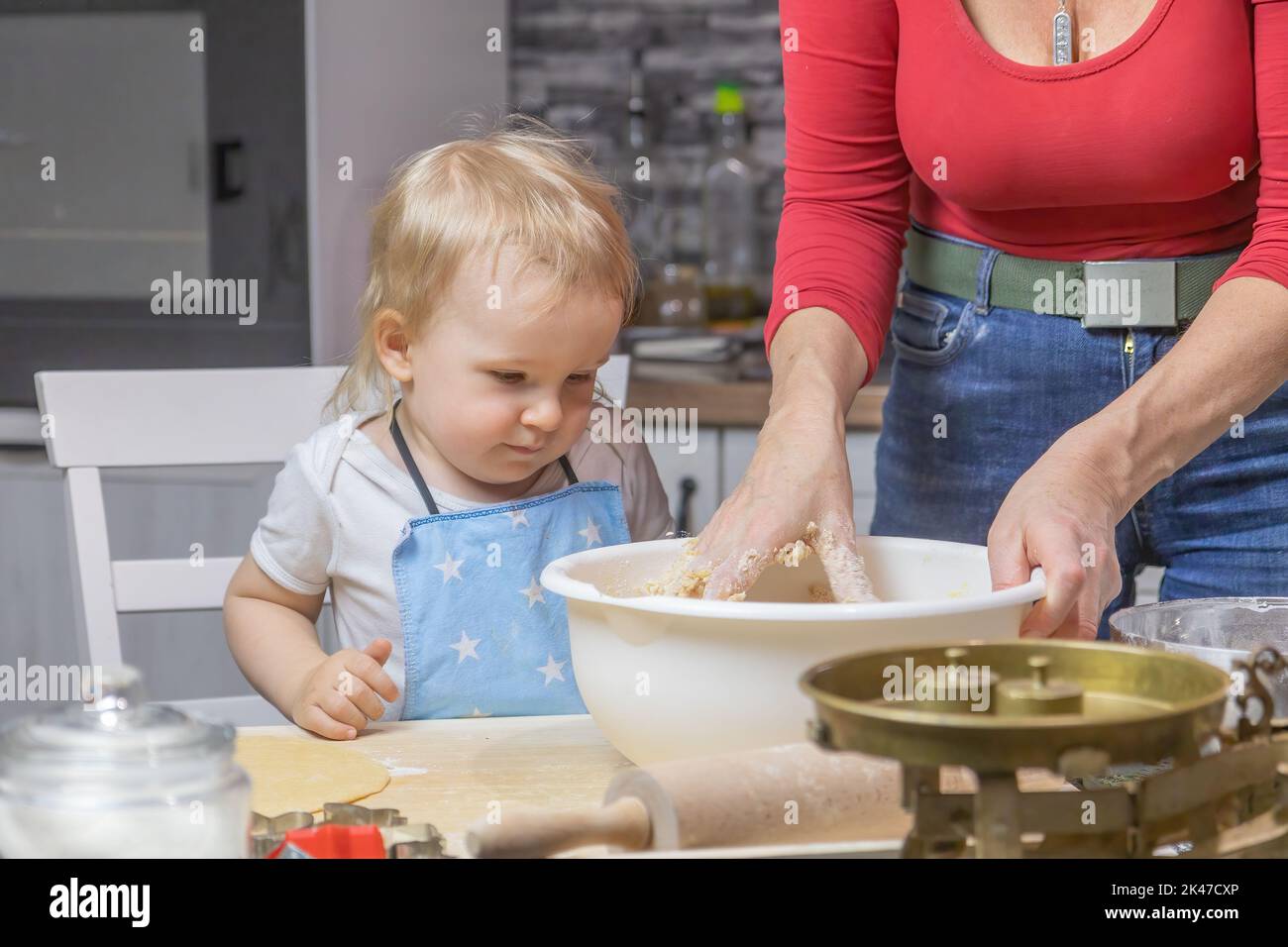 Adorable little child boy is helping mom baking cake in domestic ...