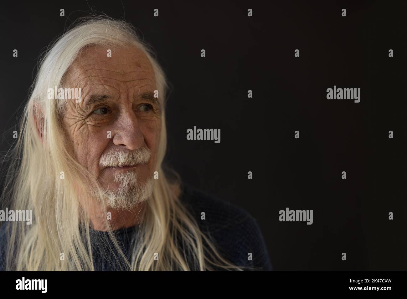 Smiling beautiful old man - rock fan - is posing with gray long hair ...