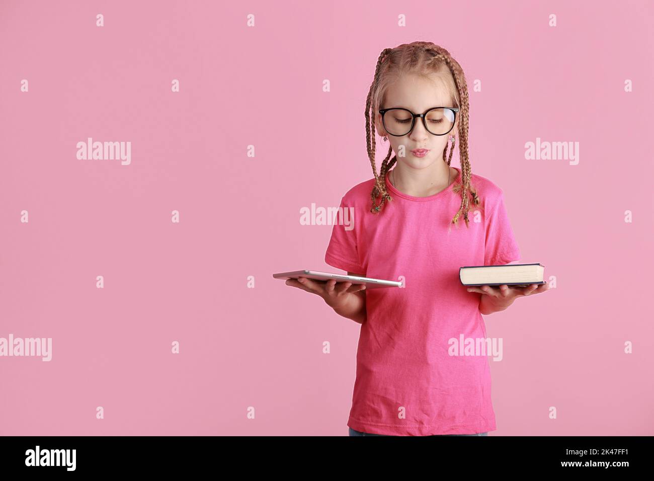 Books Vs Gadgets Concept. Puzzled school girl in glasses holding ...