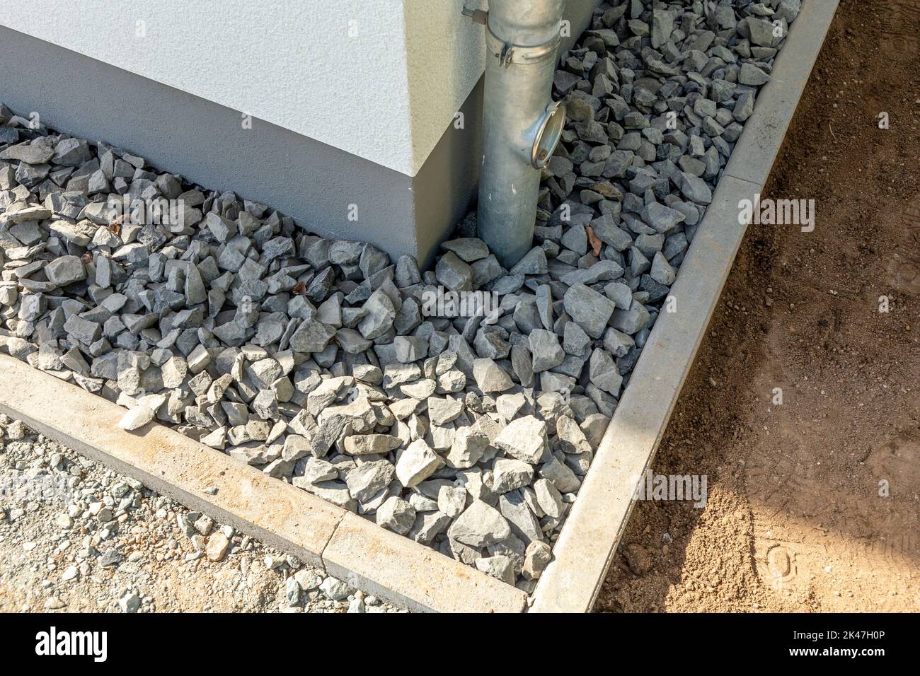 corner of a new built douse with curbes and a rain pipe collecting roof ...