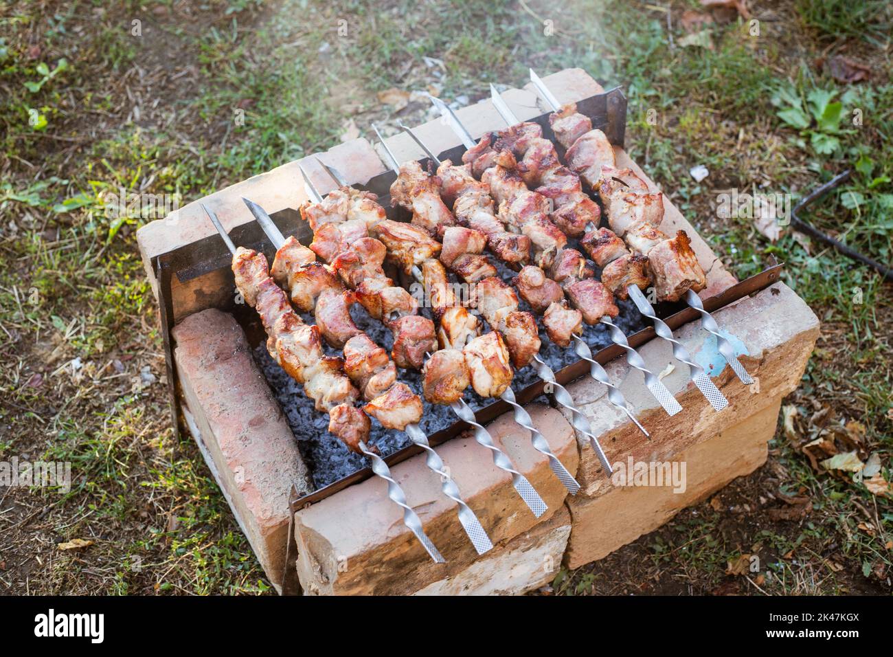 Pork skewers are fried on skewers over charcoal on a homemade brick ...
