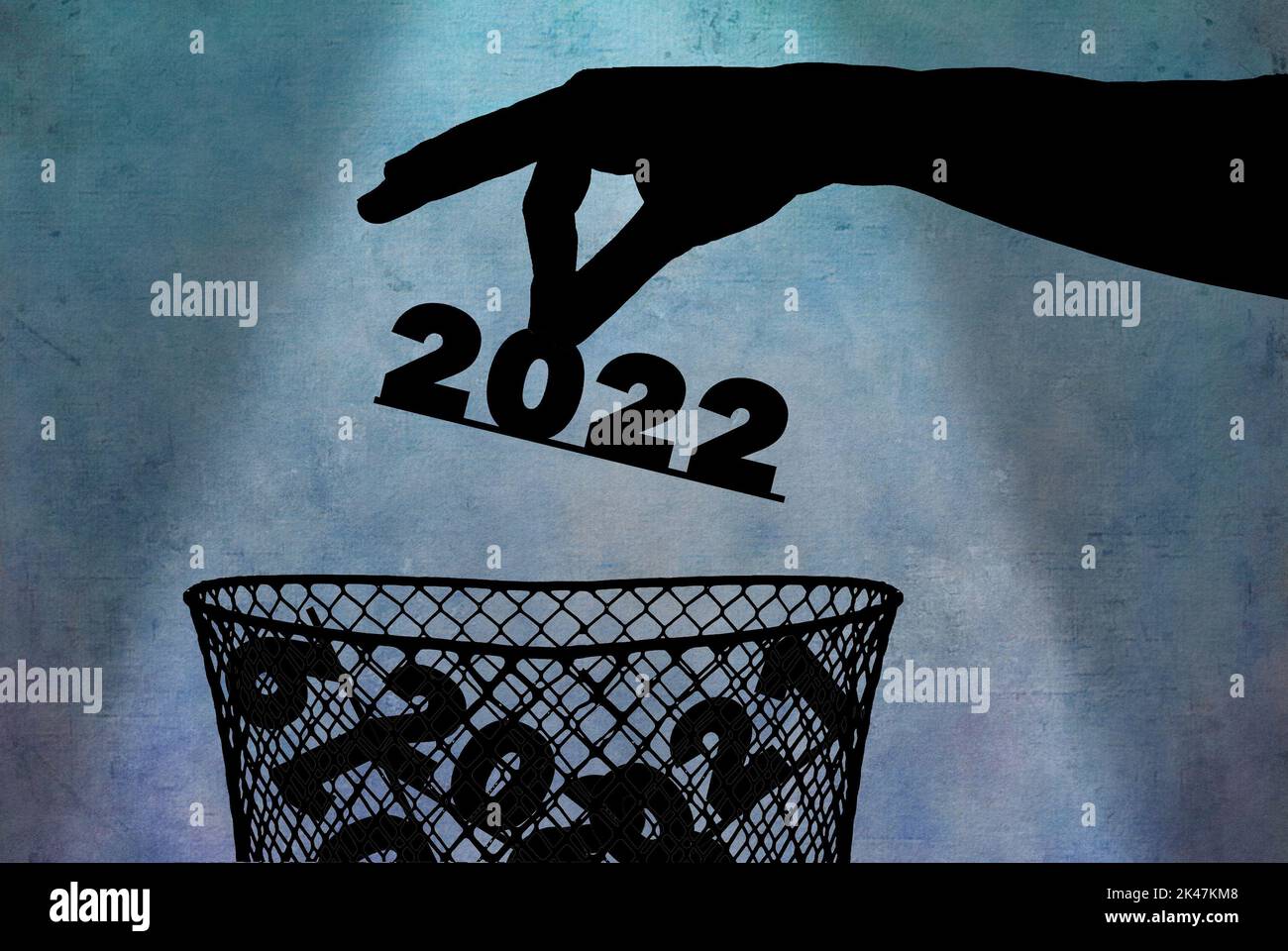 A hand is silhouette drops the number 2022 into a trash can already ...