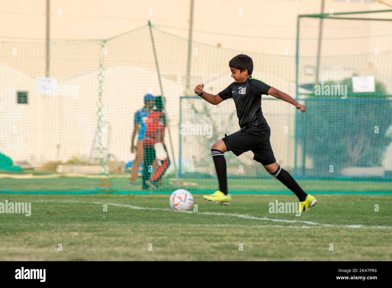 Young Kid Footballer playing in street ground with FIFA Qatar Official ...