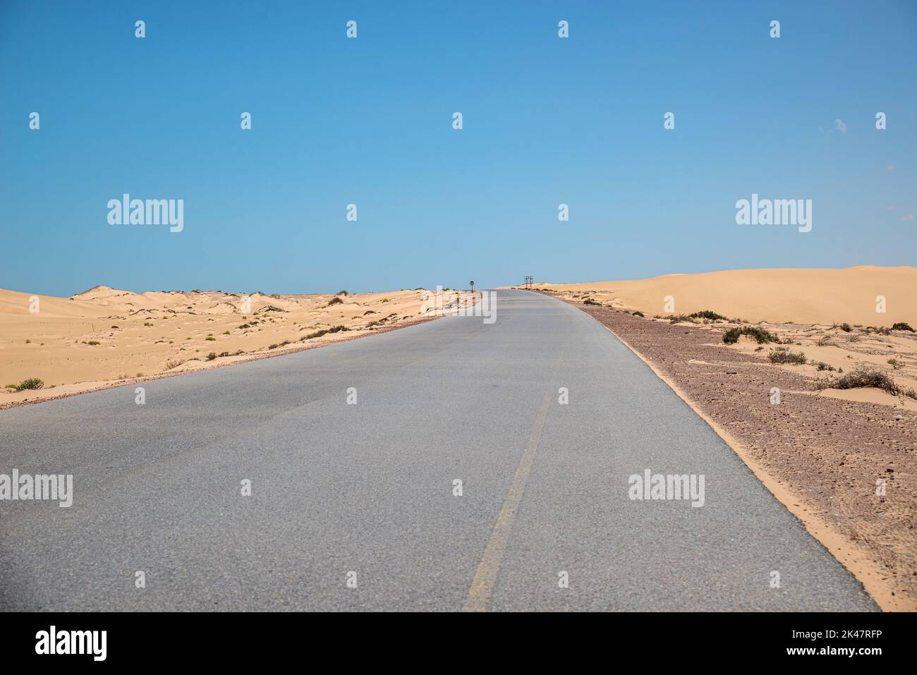 A road crossing red dunes of Wahiba Sands desert is Southern East Oman ...