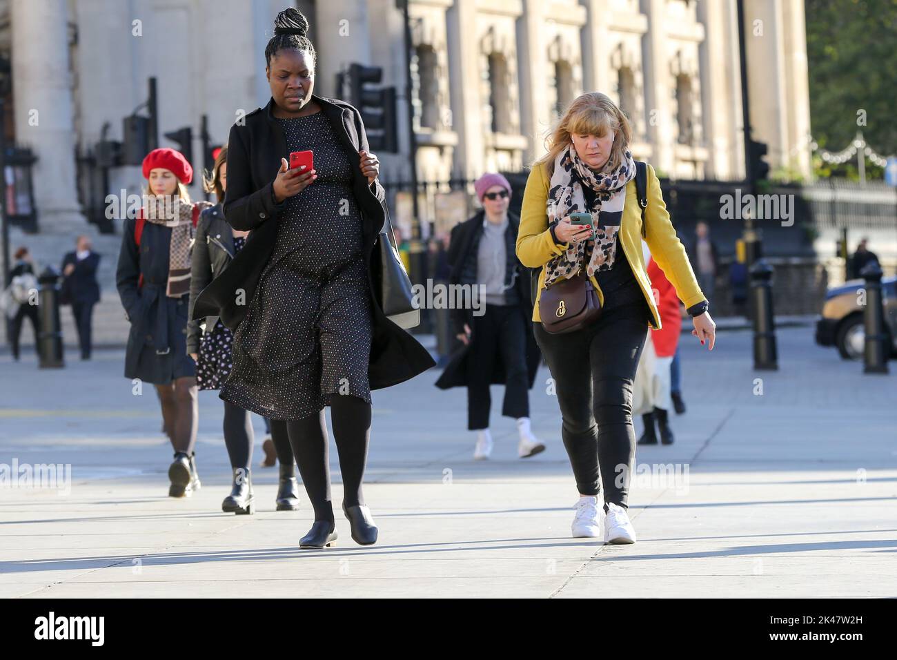 Women seen looking at their mobile phones while walking in central ...