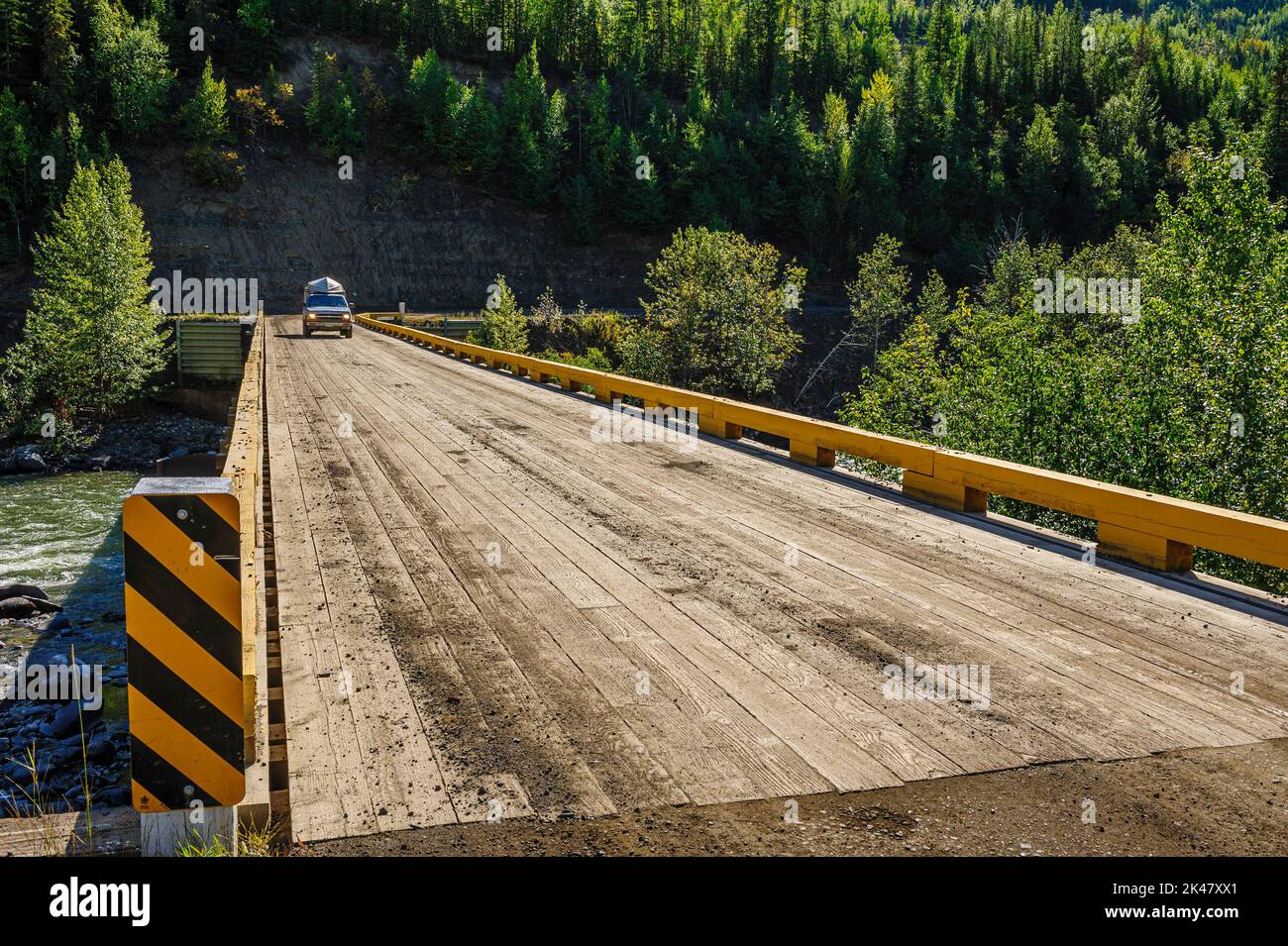 A pickup truck with a boat on top crossing a bridge over the Tuya River ...