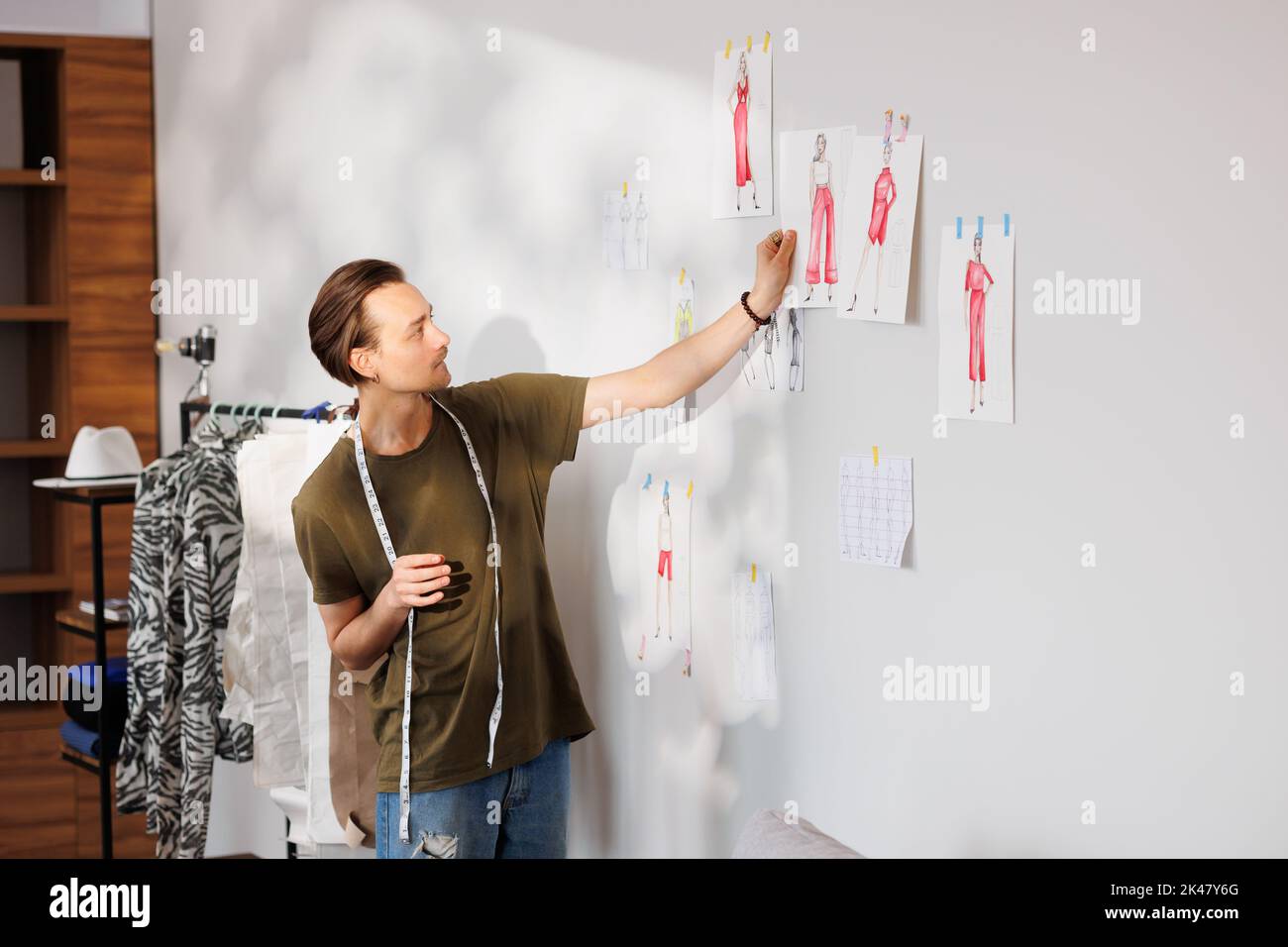 A young guy, a fashion designer, looks at his sketches of the new ...