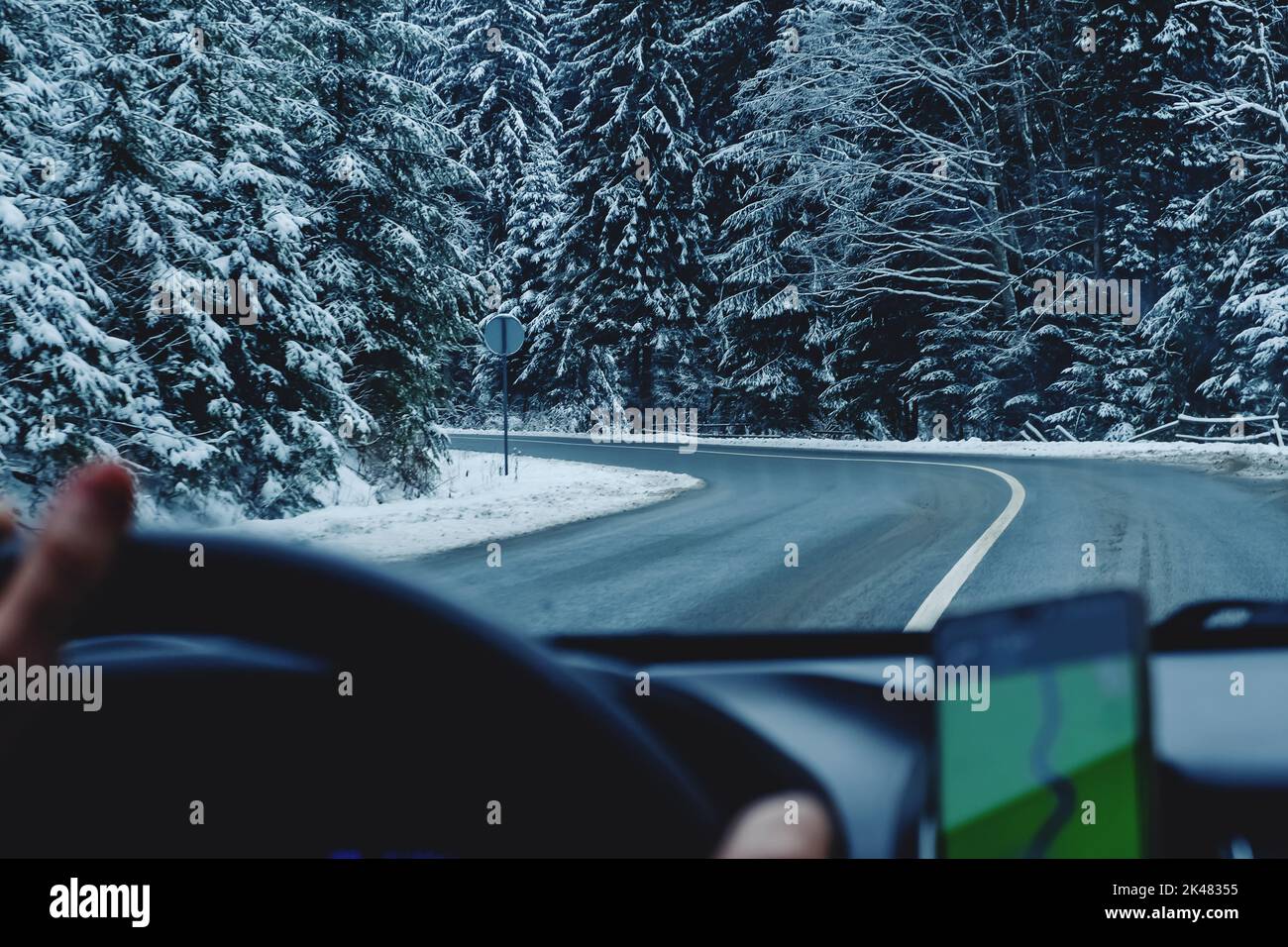 Driving through the winter snowy forest, view from the drivers side ...