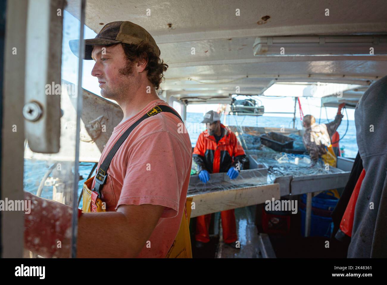 A fisherman looking out to sea while on board a commercial fishing boat ...
