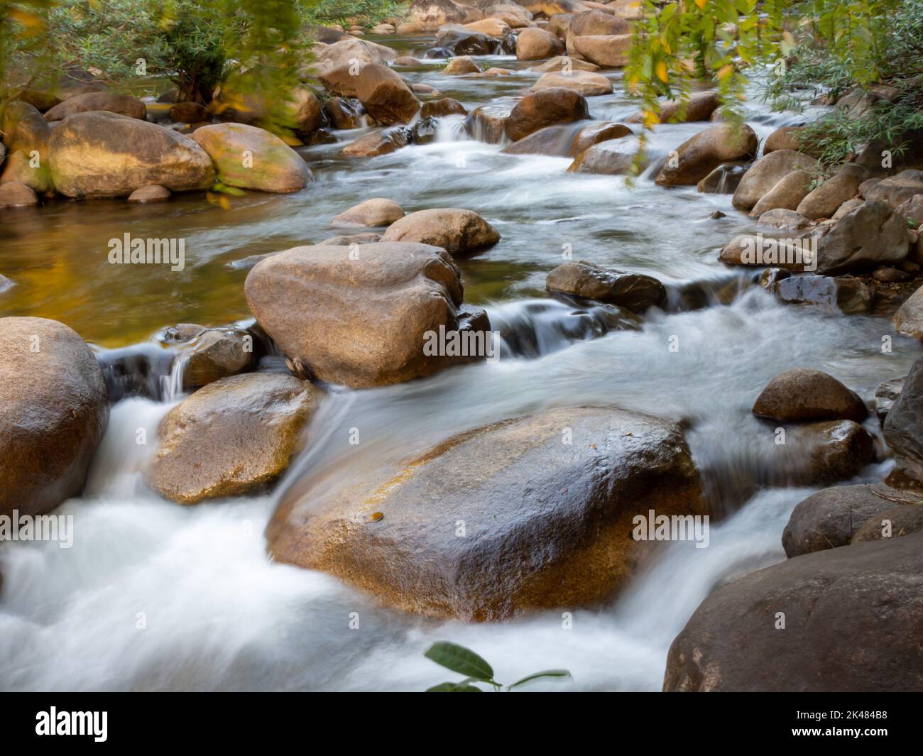 A long-exposure shot of a small creek flowing through a brown rock. And ...
