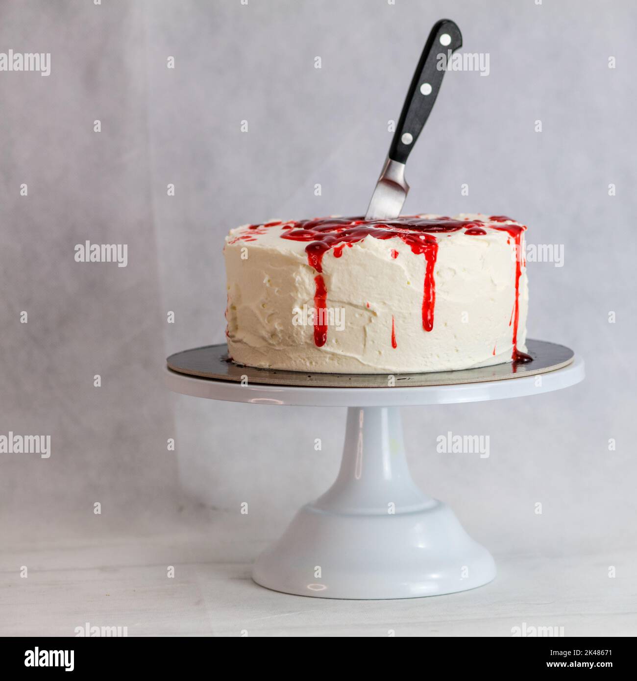 Bleeding monster cake with knife on cake stand Stock Photo - Alamy