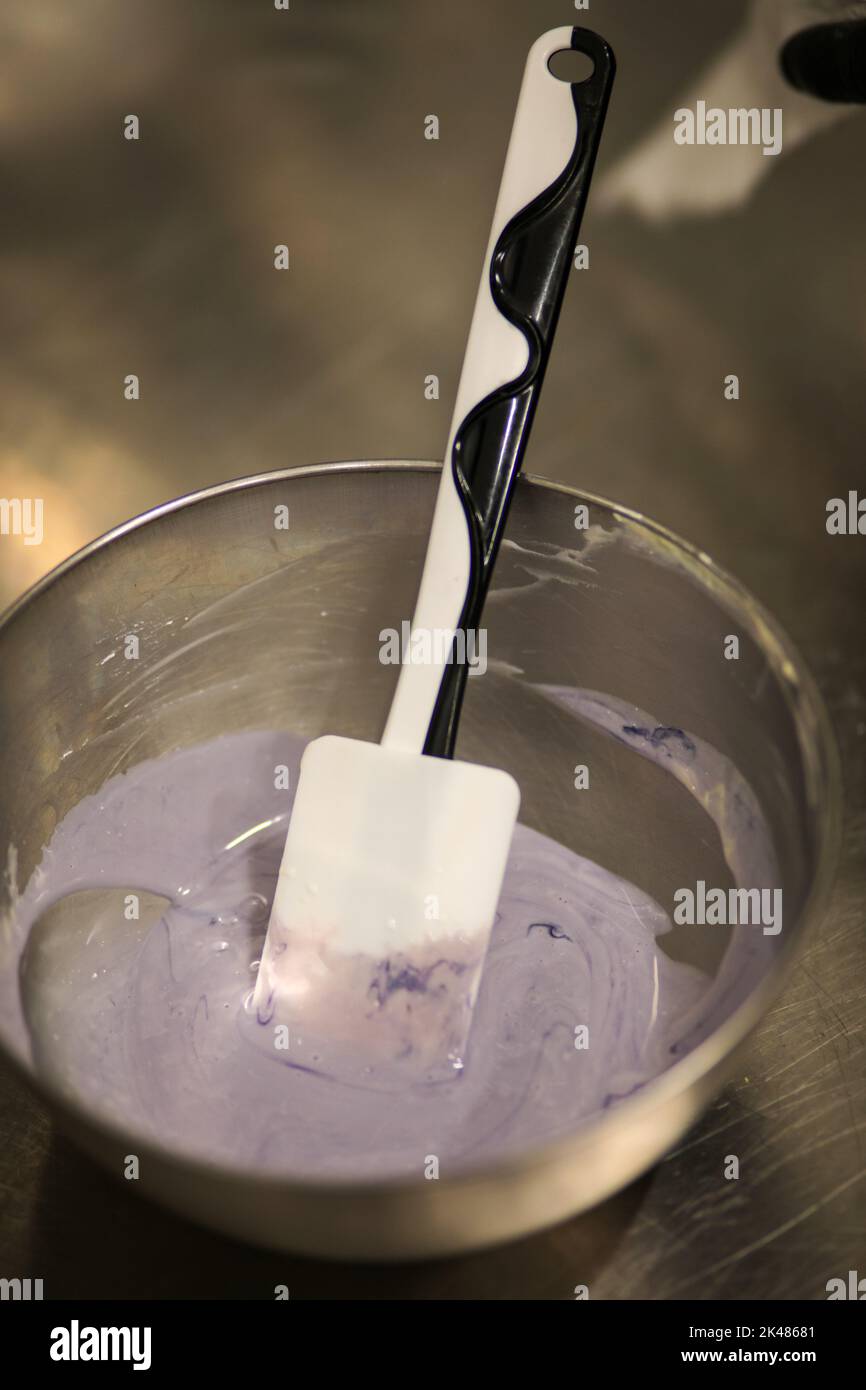 chef making for icing a lilac drip cake in the professional kitchen lab ...