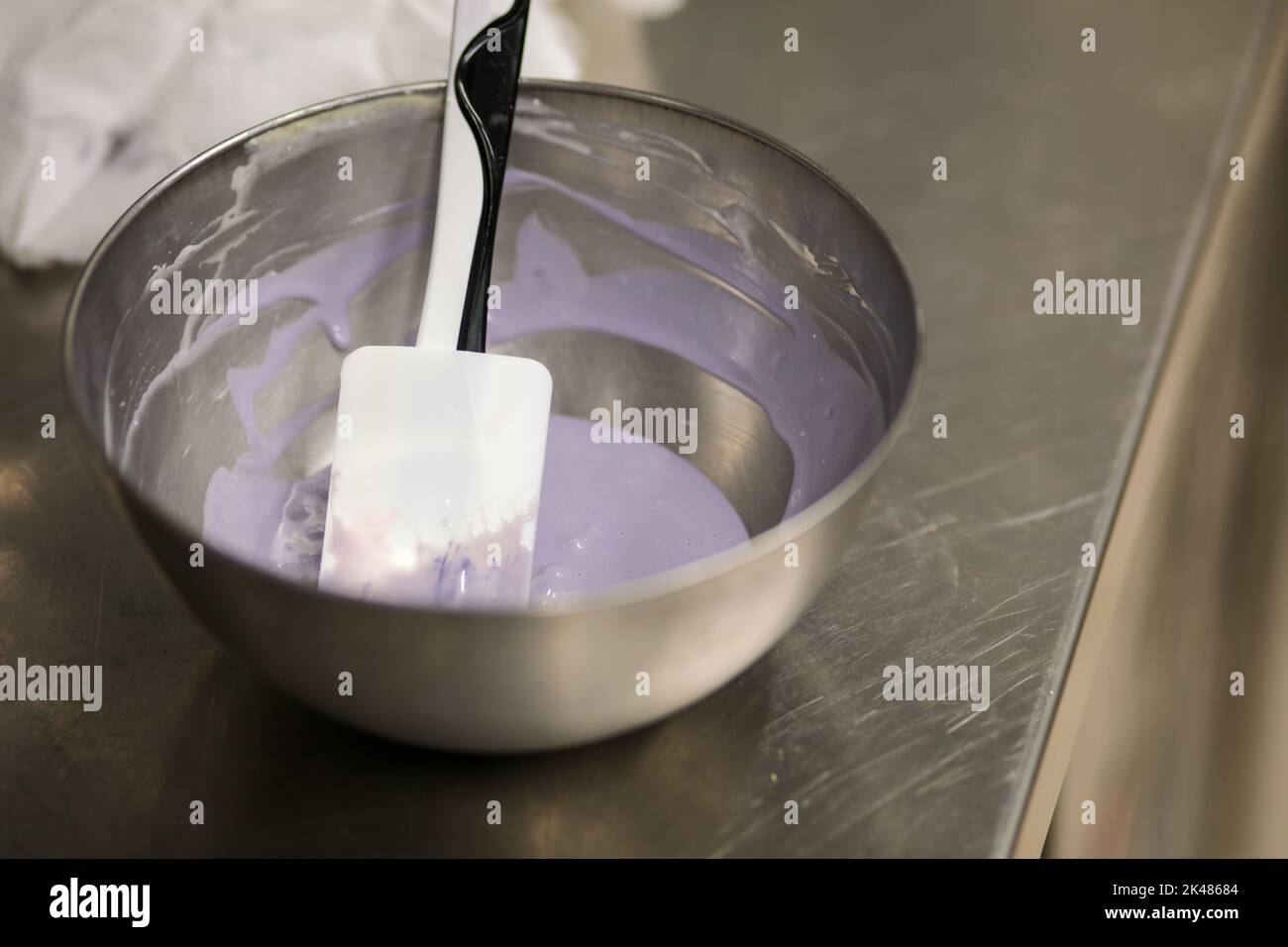 chef making for icing a lilac drip cake in the professional kitchen lab ...