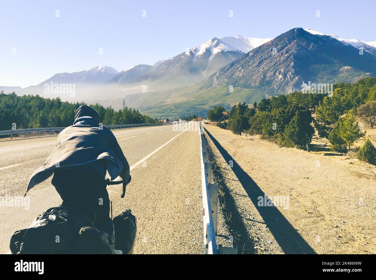 Back view close up cyclist on touring bicycle rides fast downhill ...