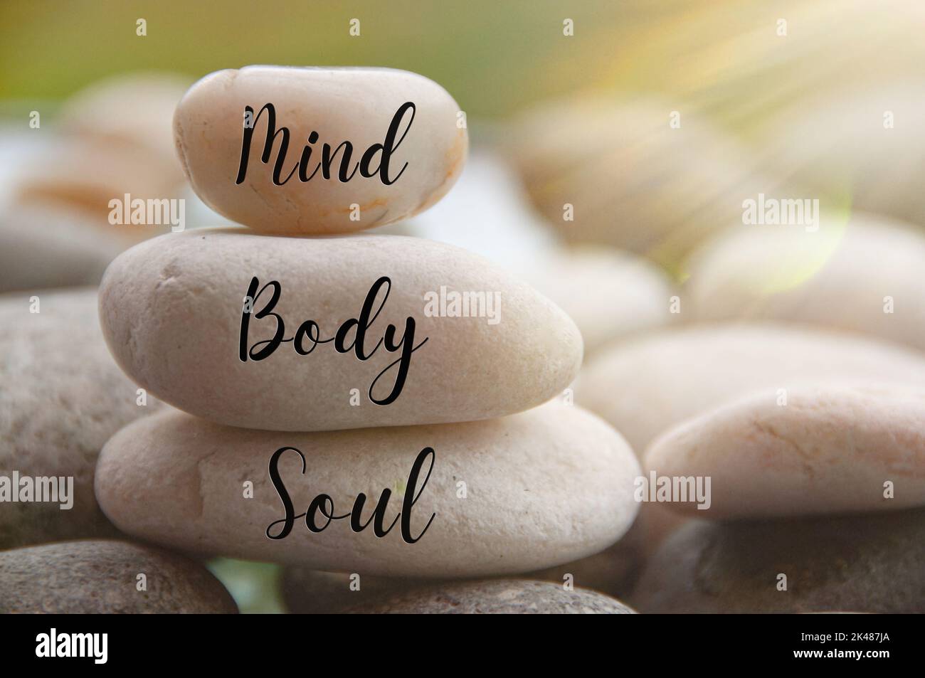 Light shining on zen stones with words Mind, Body, Soul on blurred ...