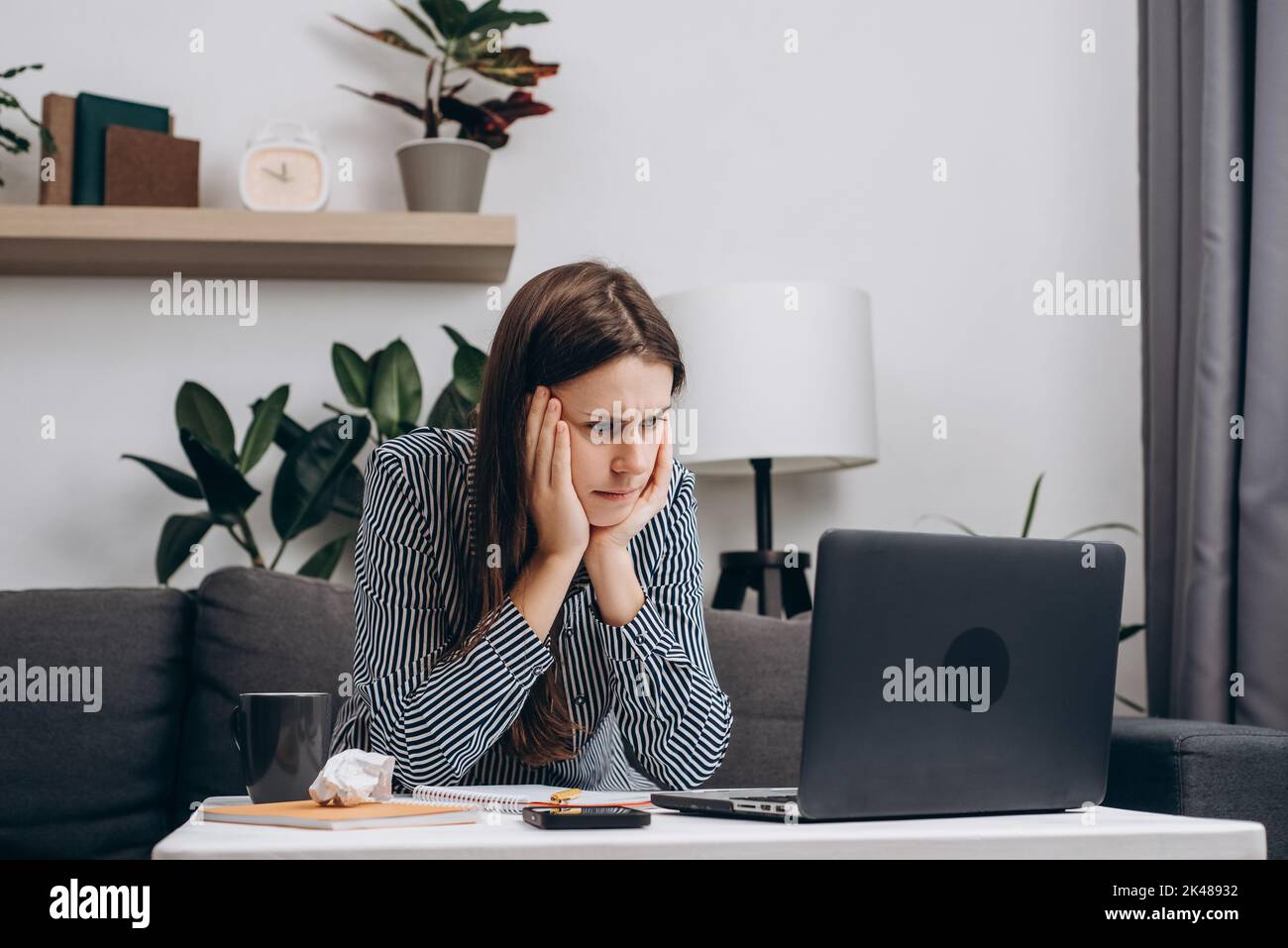 Thoughtful girl 20s working or studying on computer tech. Serious ...