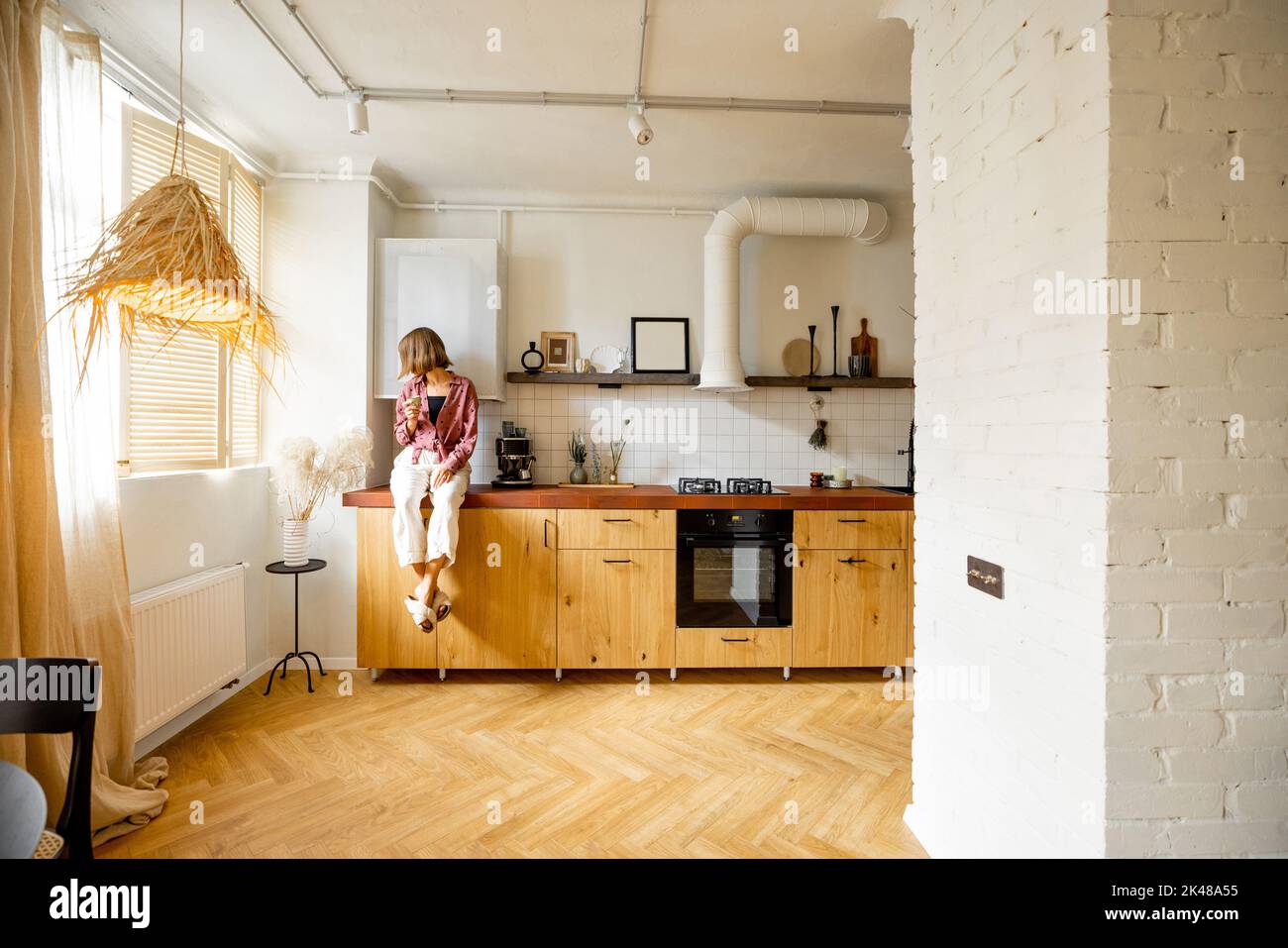 Modern kitchen interior with person sitting on table top Stock Photo ...
