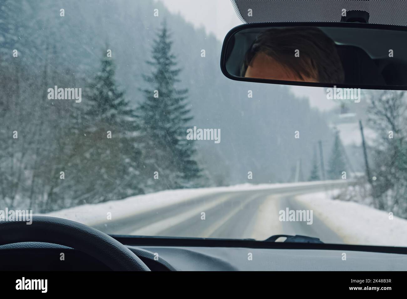 Driving through the winter snowy forest, view from the drivers side ...