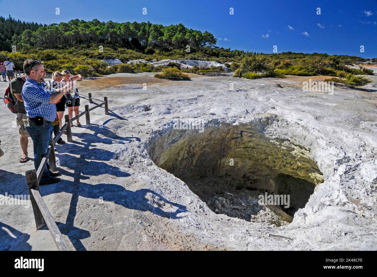 Visitors stand behind a roped off safety barrier at a crater called ...