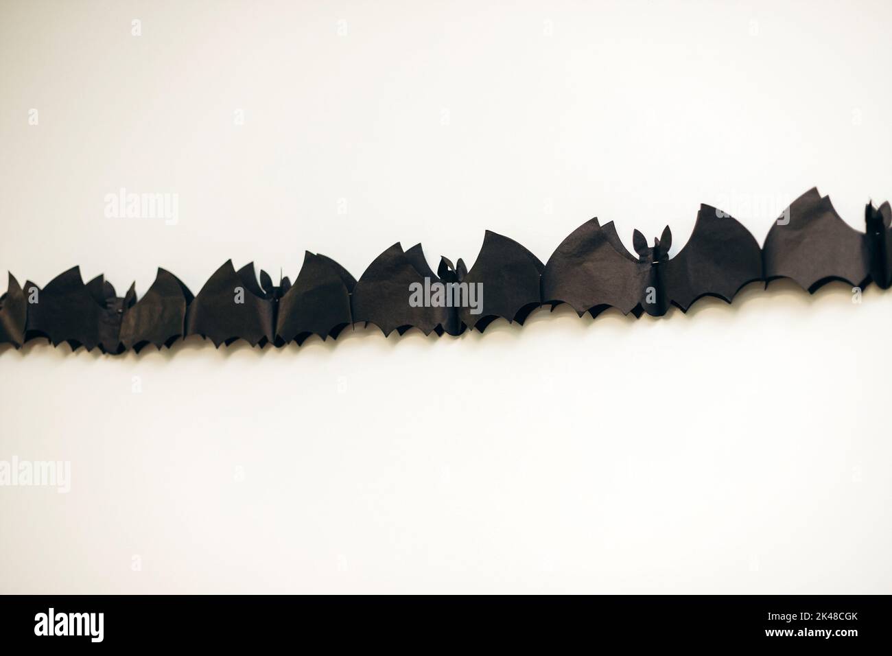 Line of Black Paper Bats on white wall. Halloween decor, paper bats ...