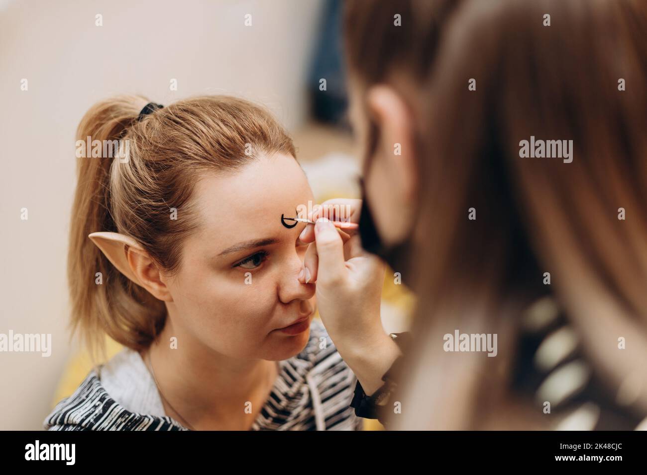 Make-up artist makes month moon on forehead face of young attractive ...