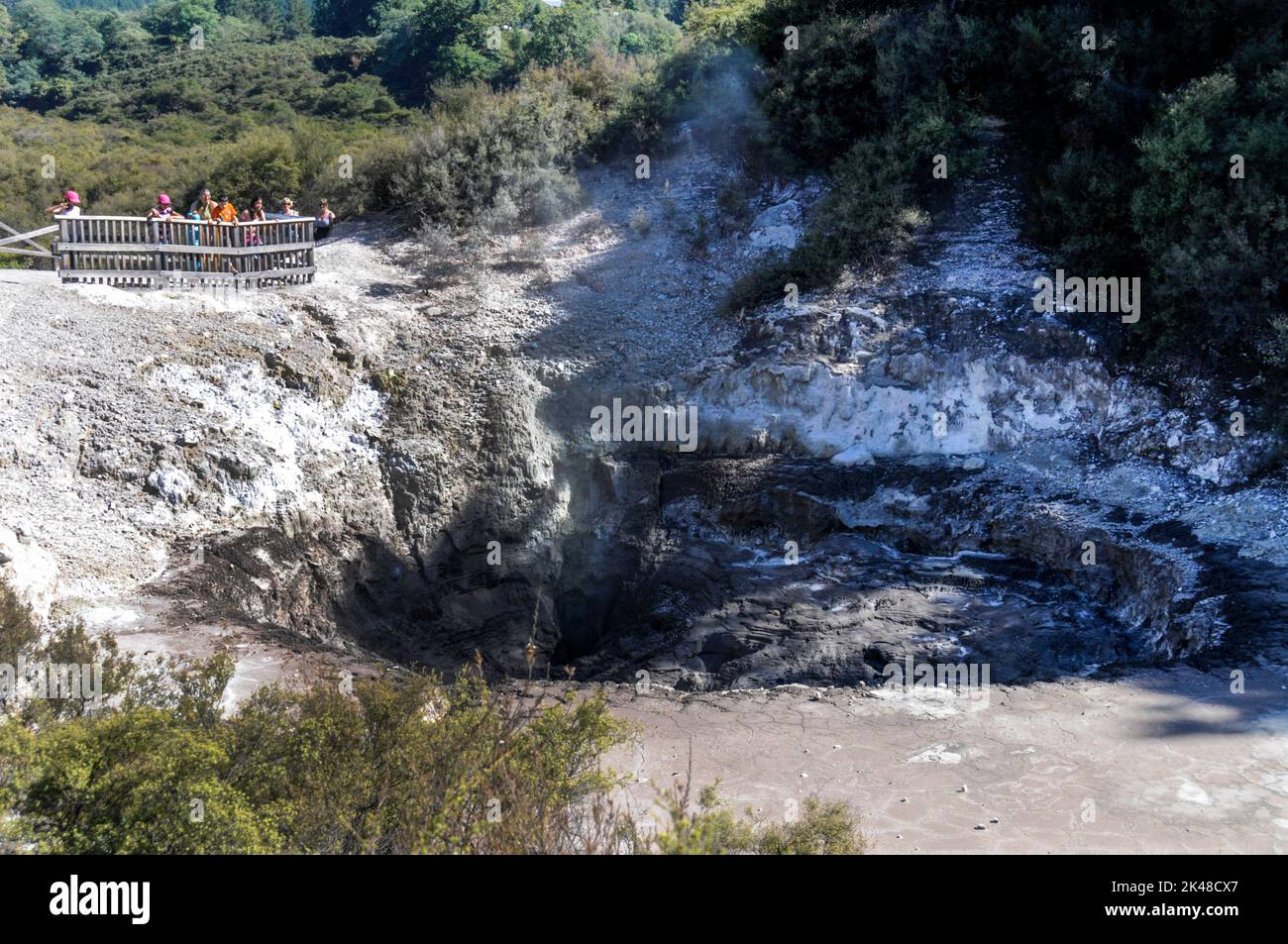 A group of children and their parents stand behind a safety fence ...