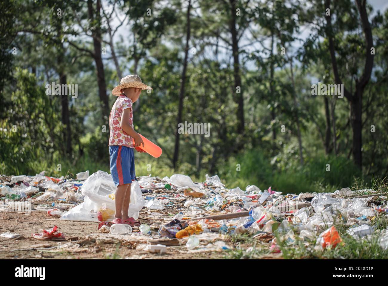 A poor boy collecting garbage waste from a landfill site. Concept of ...
