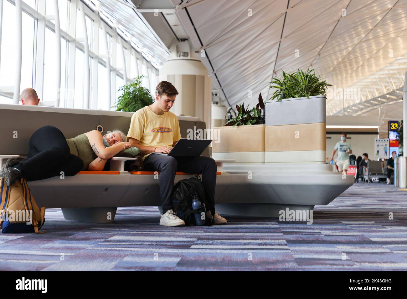 Caucasian man and woman sleep or use computer when waiting for airplane ...